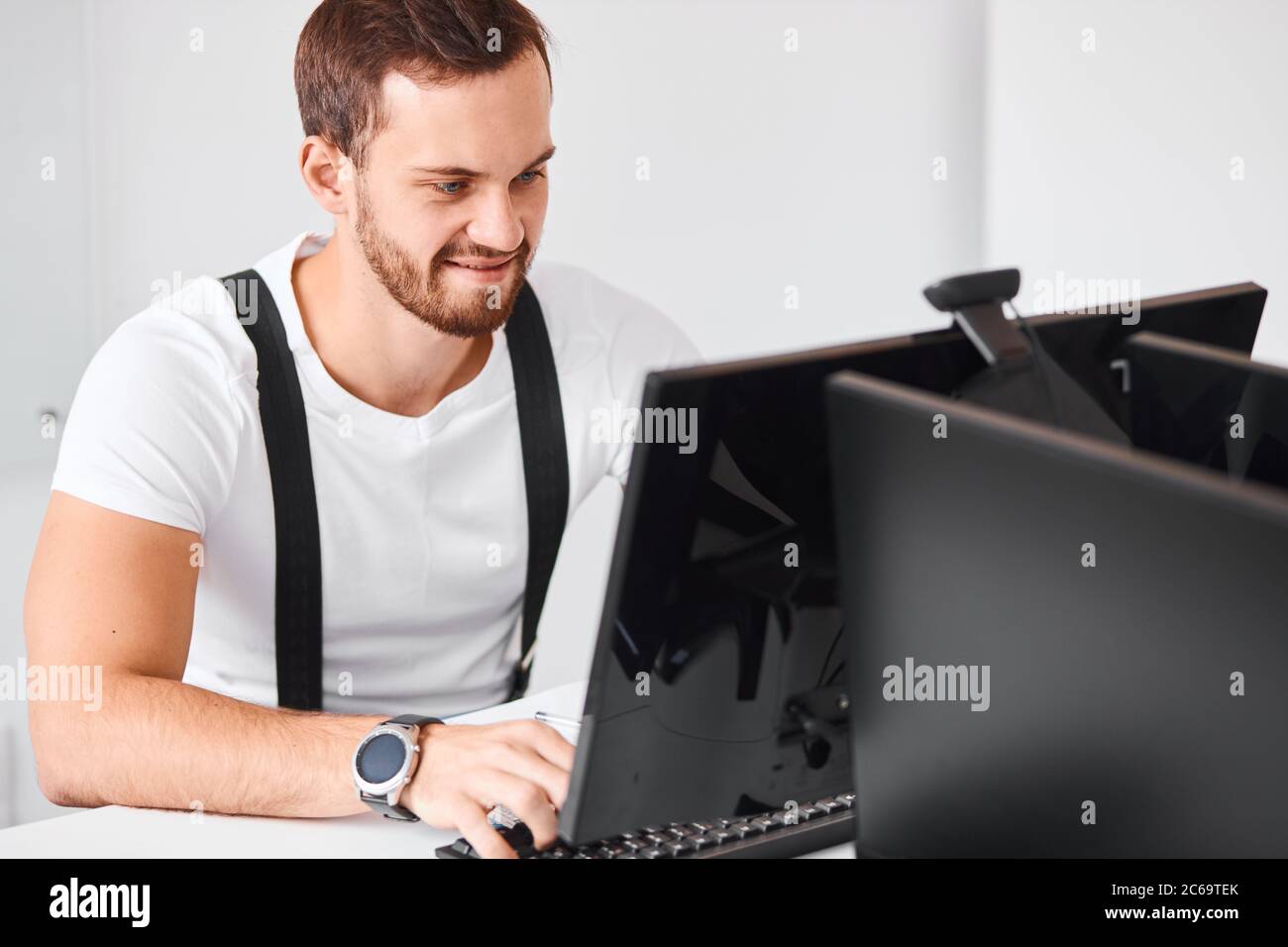 Handsome busy man working on computer, look at screen of computer ...