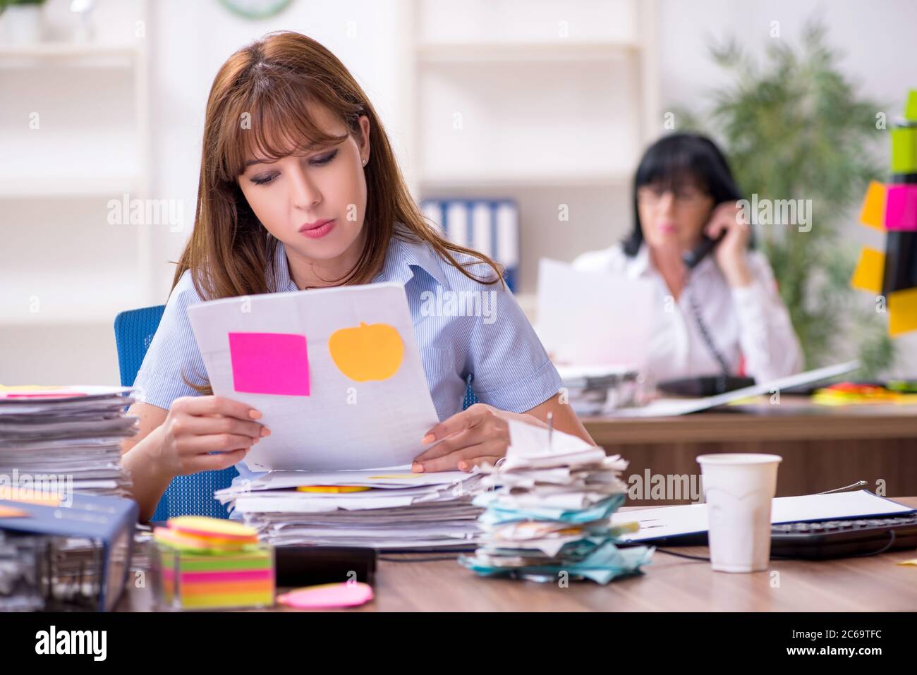 Two employees and excessive work in the office Stock Photo - Alamy