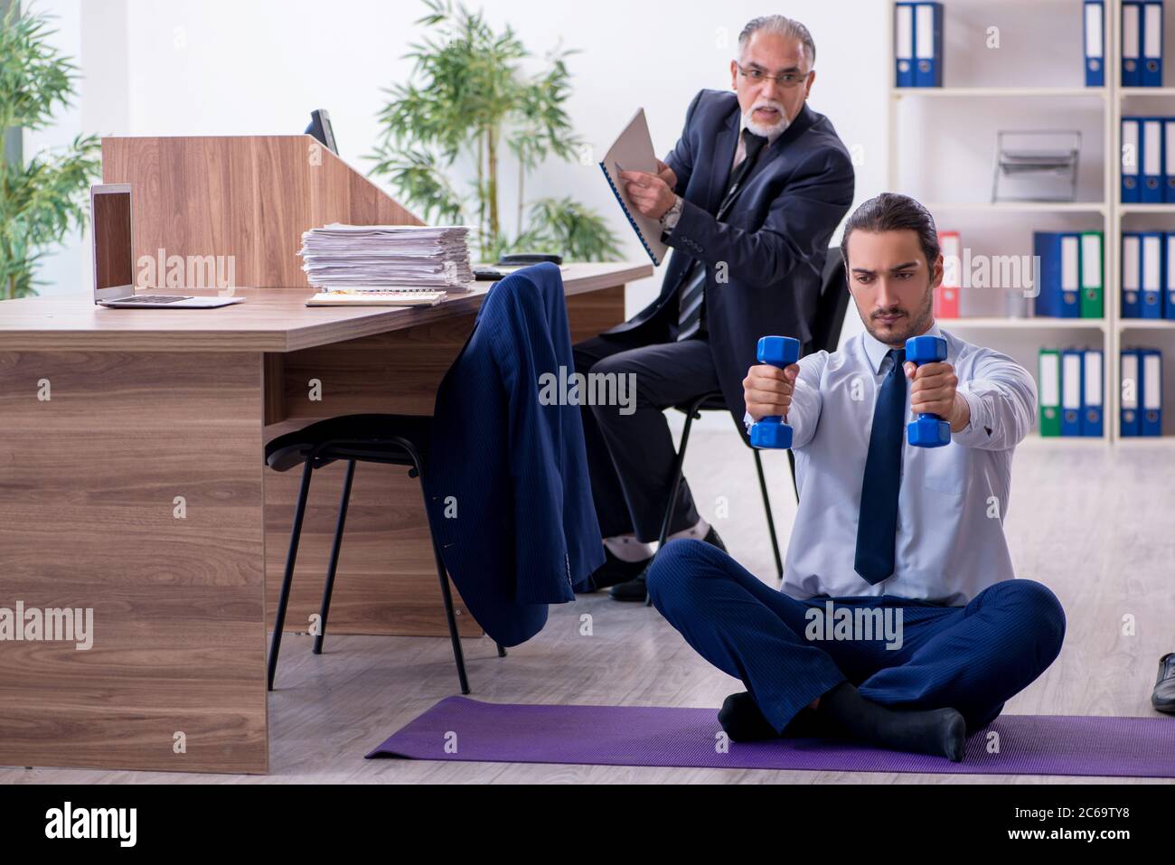Two employees doing physical exercises at the workplace Stock Photo - Alamy