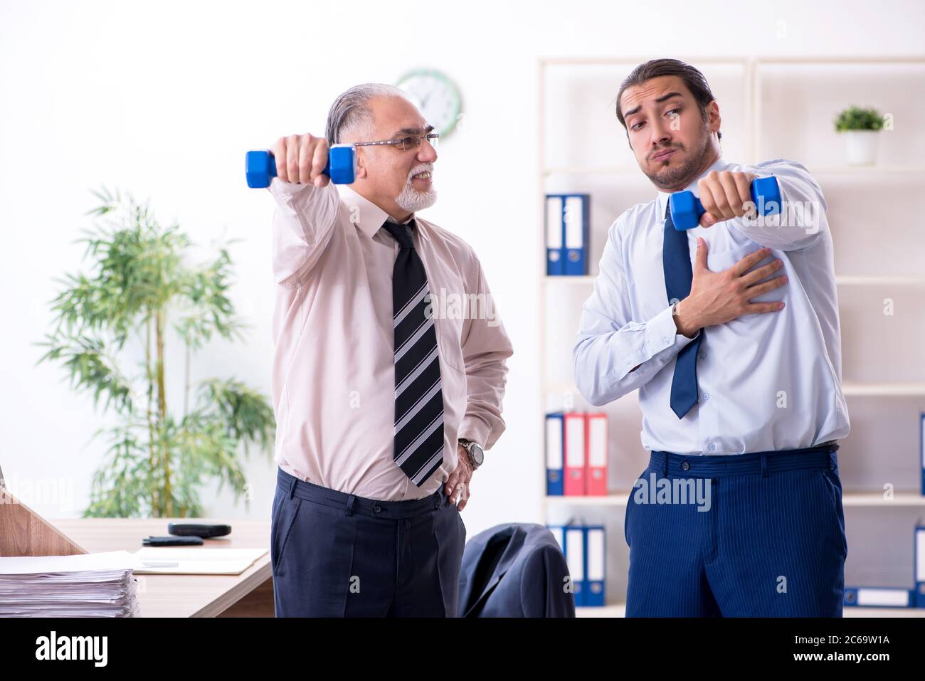 Two employees doing physical exercises at the workplace Stock Photo - Alamy