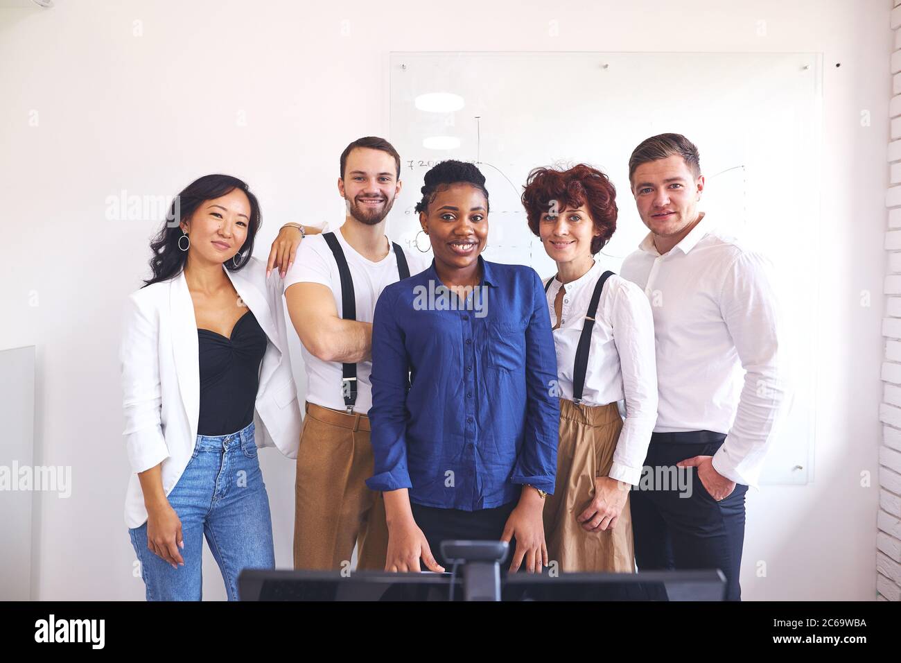 African leader posing in office together with multi-ethnic happy team ...