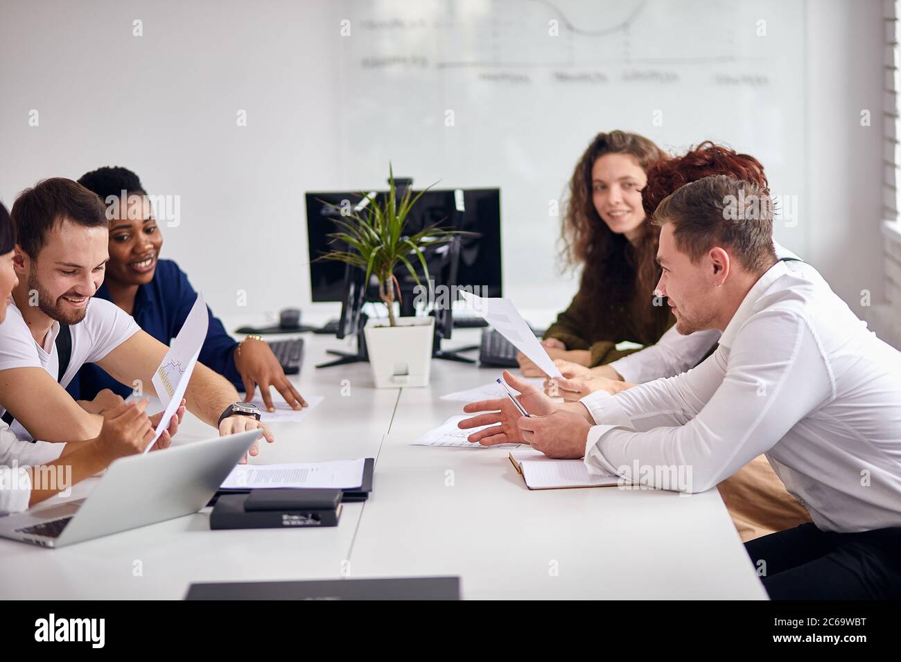 Young successful people in white clothes sit enjoy work together, laugh ...