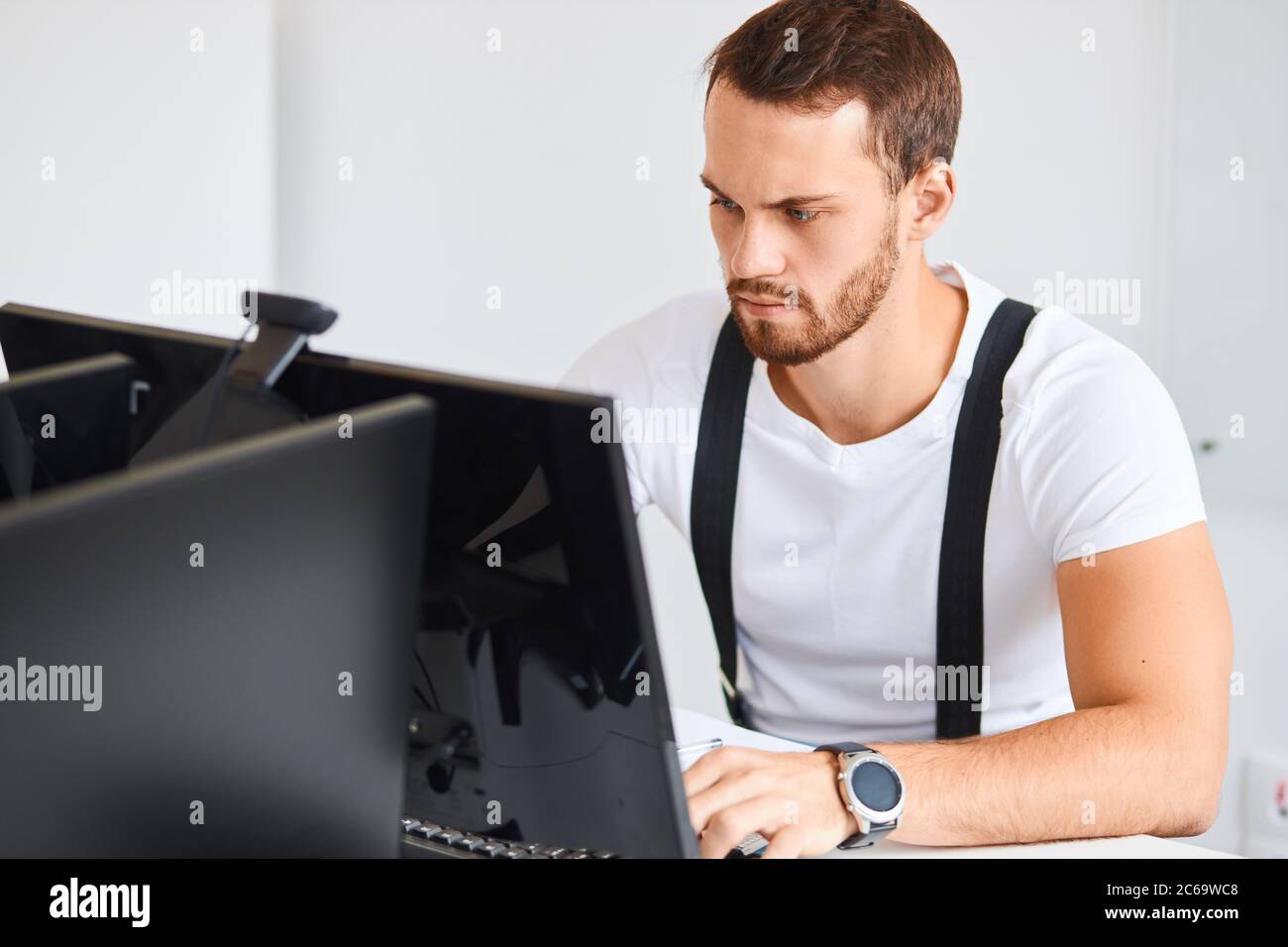 Handsome busy man working on computer, look at screen of computer ...