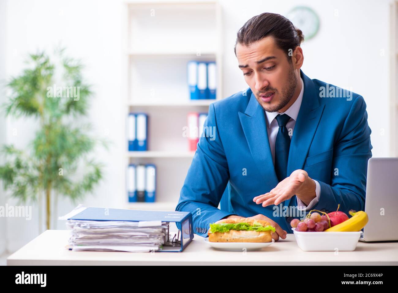 Young employee having breakfast at workplace Stock Photo - Alamy
