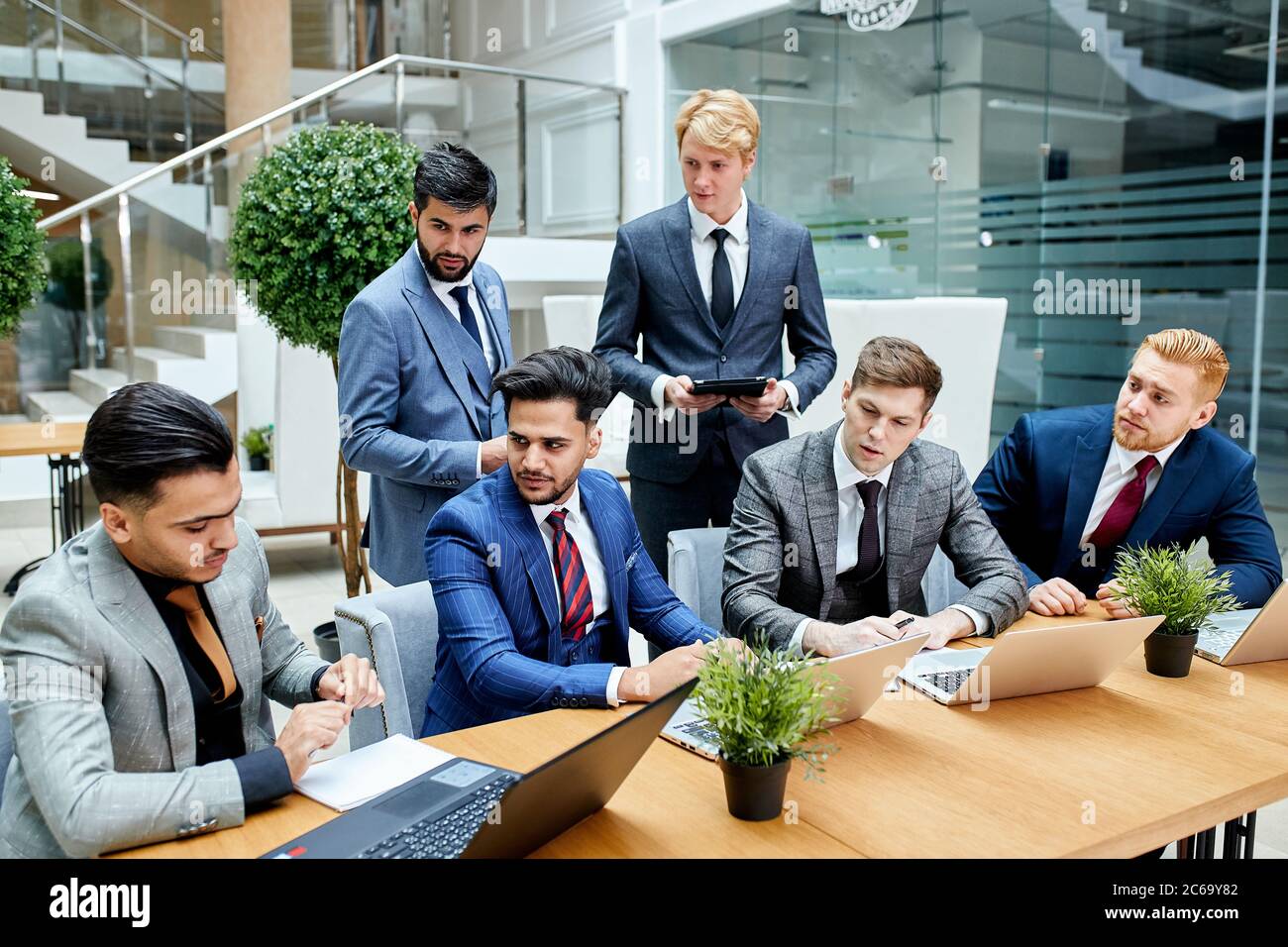 International group of businessmen sitting on table, everyone looking ...