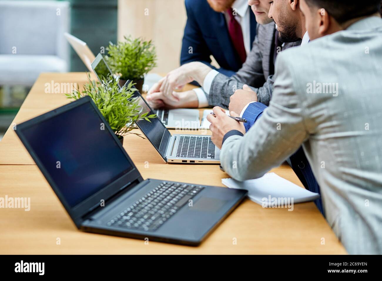 Close-up of laptop, co-working, businessmen sitting on table. Men in ...