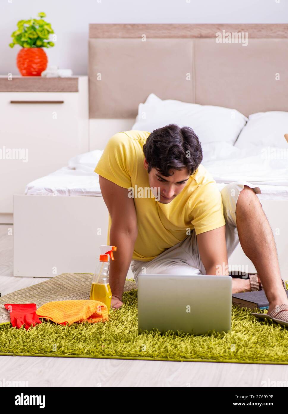 Young handsome man cleaning the bedroom and sitting at the computer ...