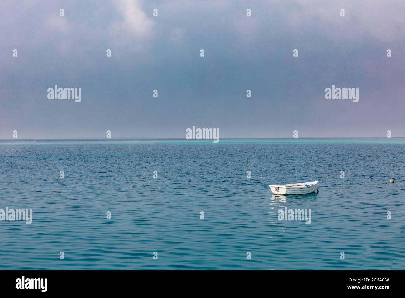 Old rowing boat marooned at sea. Lonely wooden boat, cloudy sky, calm ...