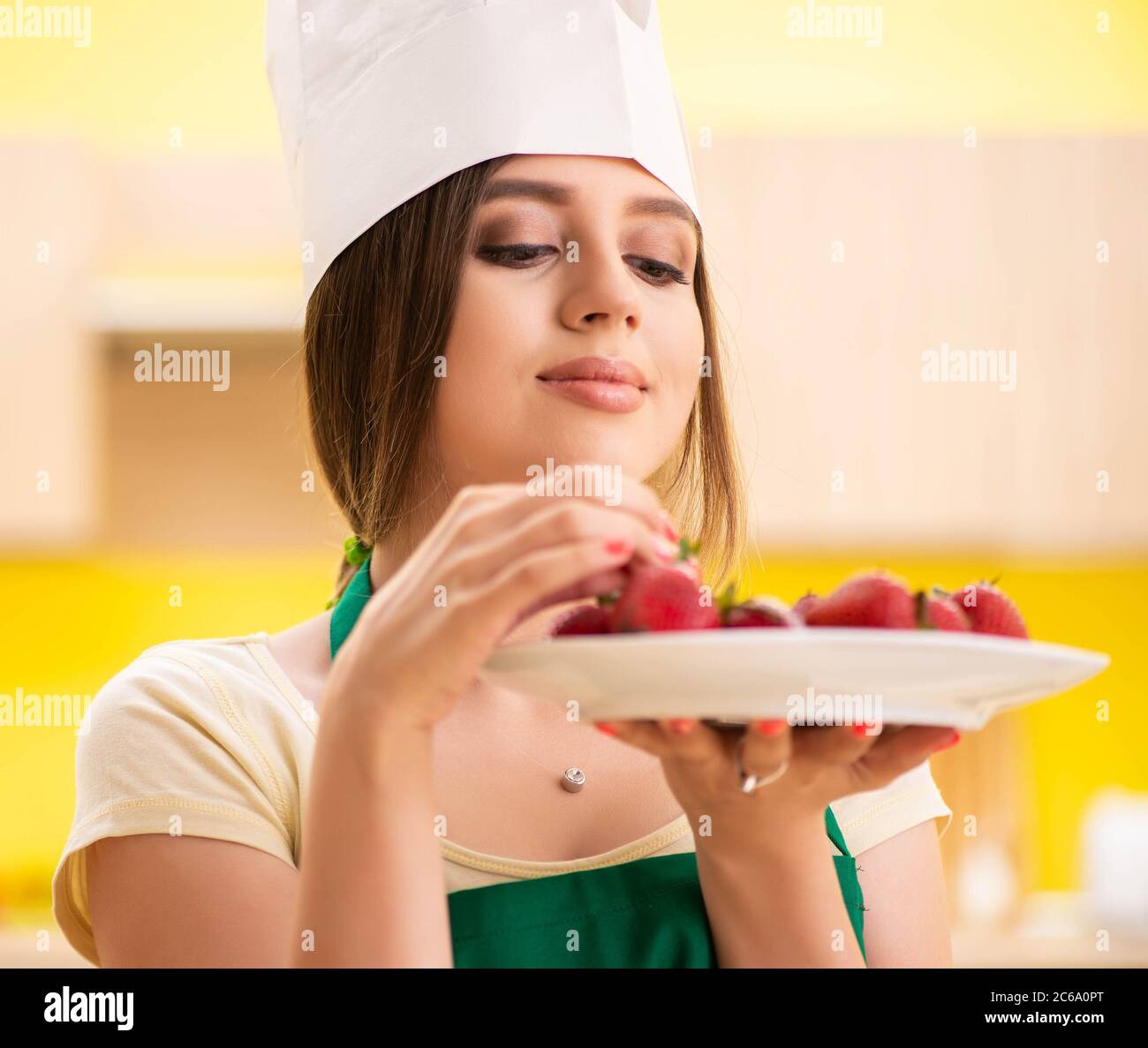 The young female cook eating strawberries Stock Photo - Alamy