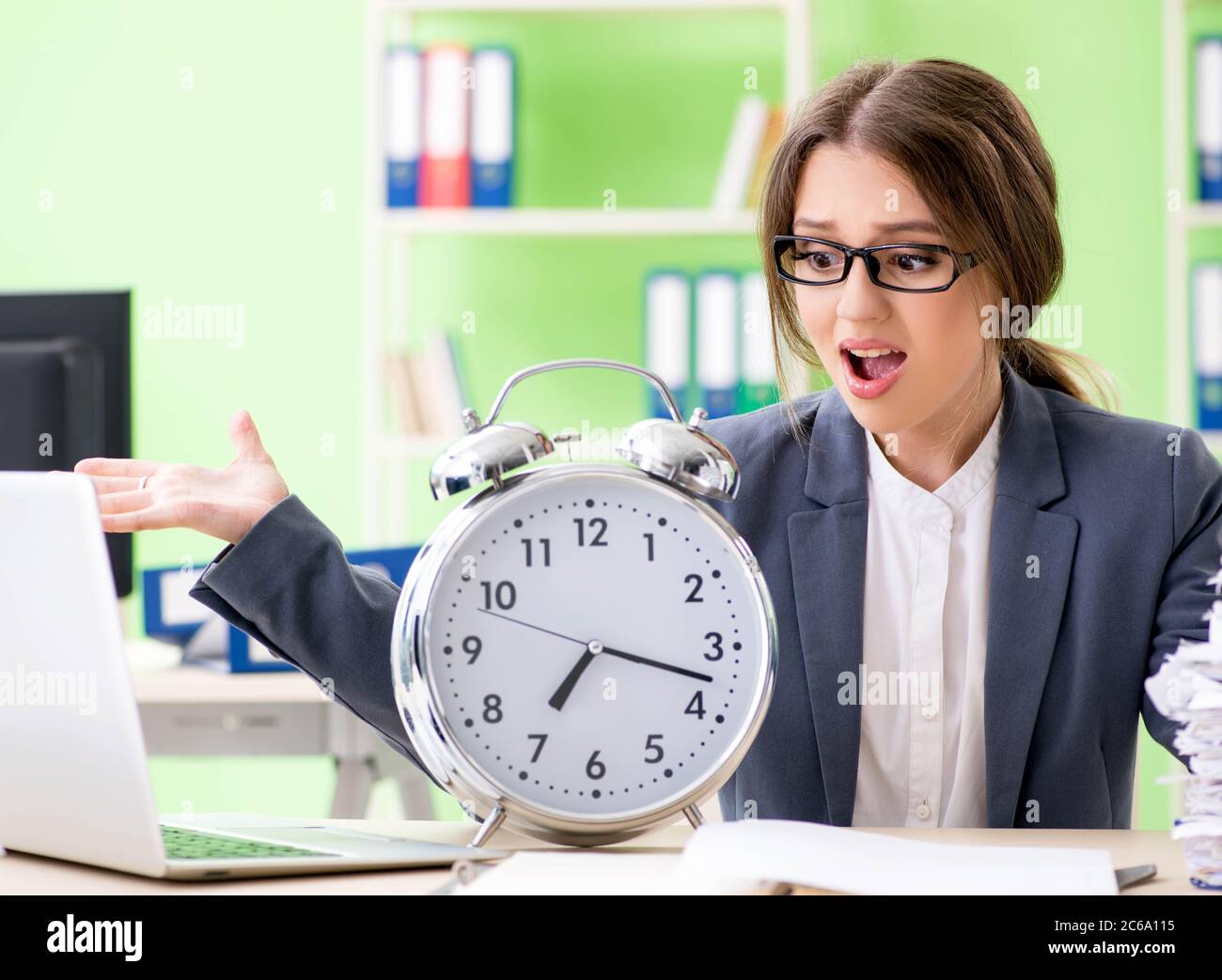 Young female employee very busy with ongoing paperwork in time ...