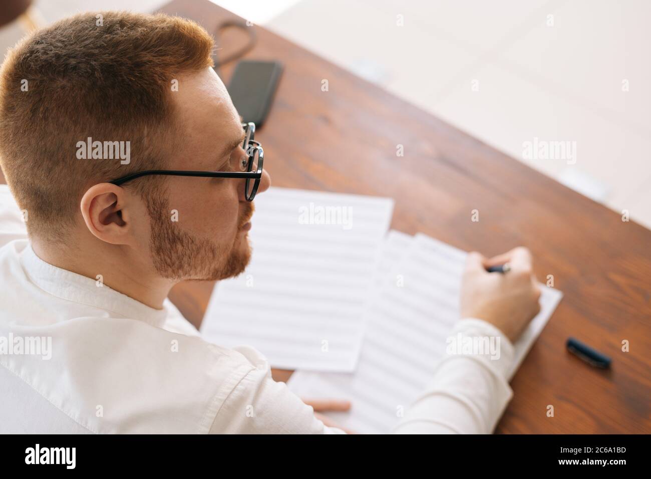 Back view of thoughtful musician wearing stylish eyeglasses thinking ...