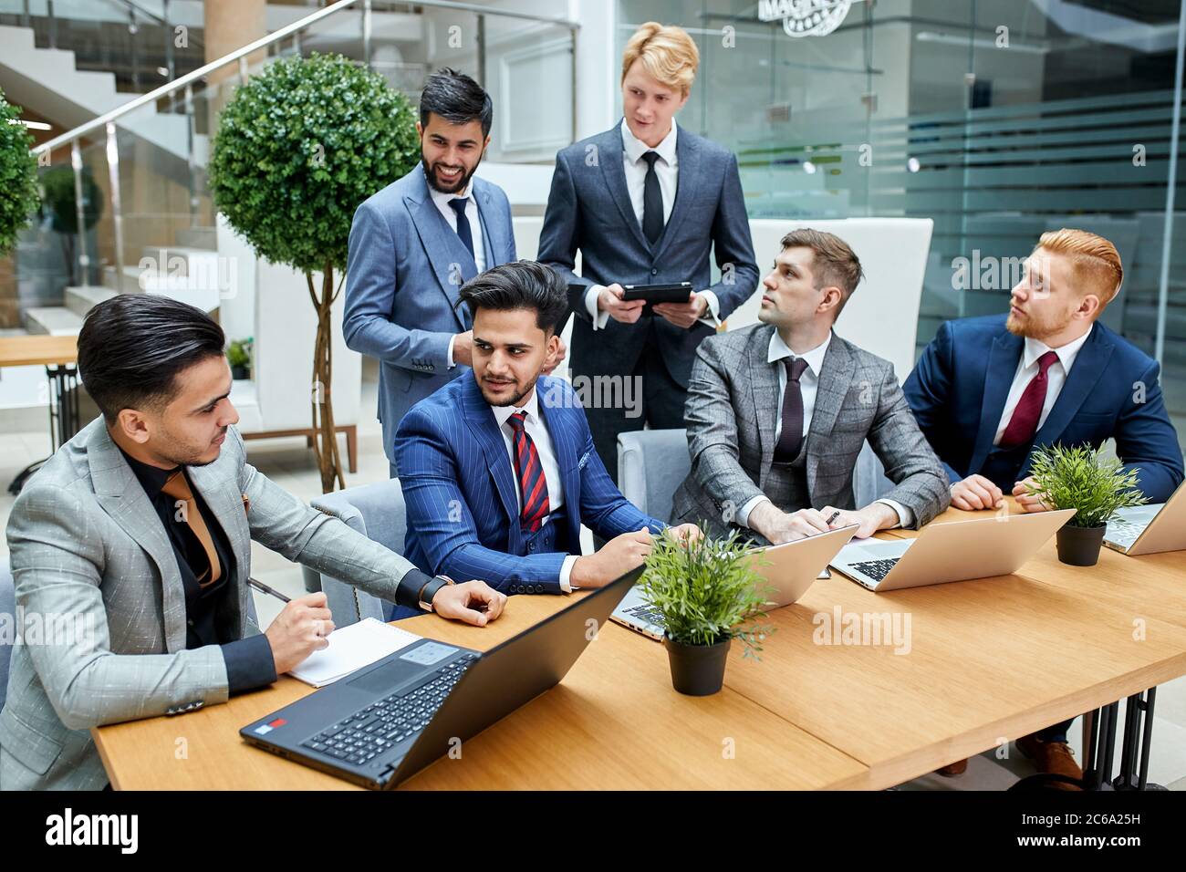 International group of businessmen sitting on table, everyone looking ...