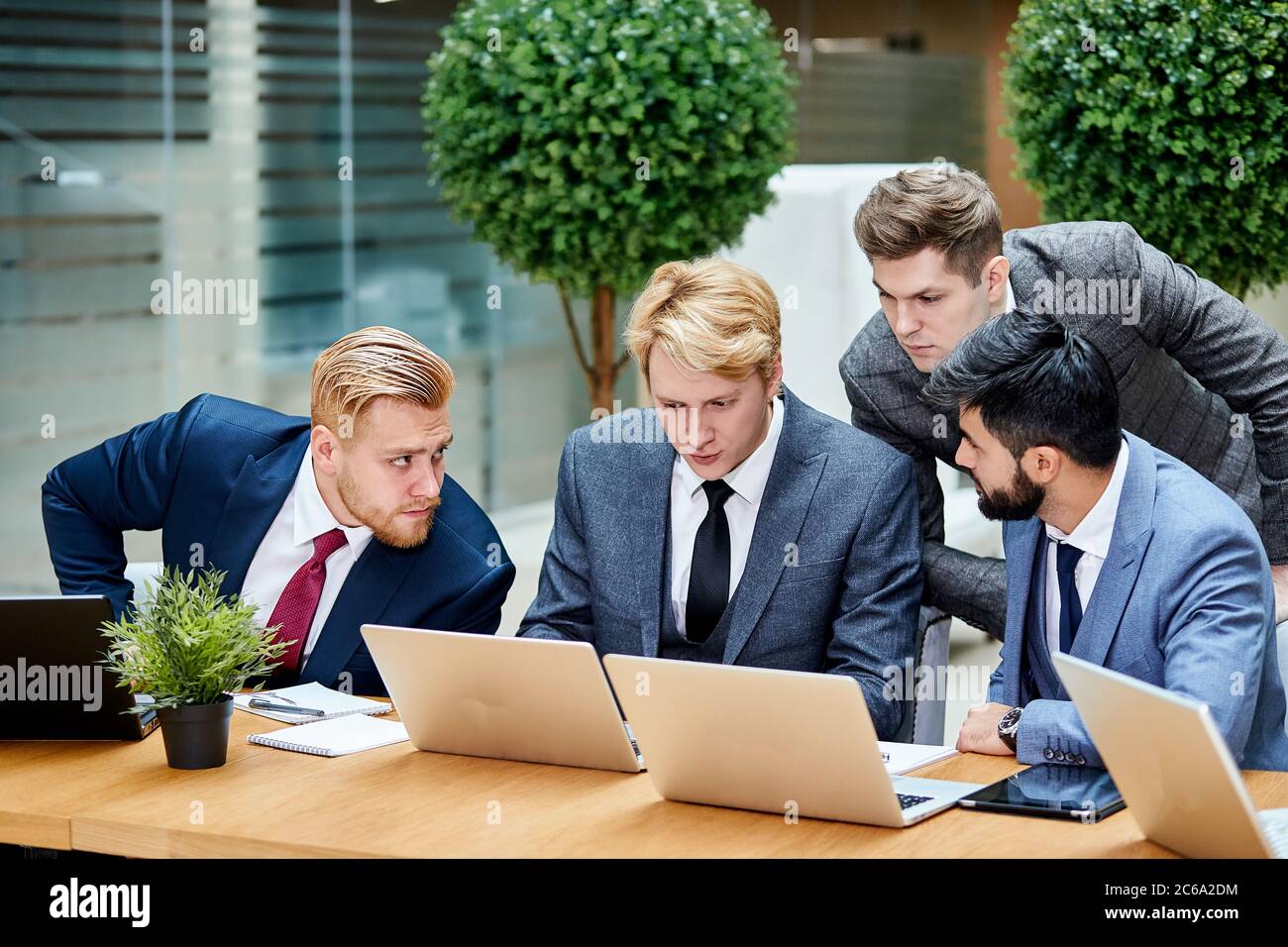 Work team gathered to discuss new project using laptop, sitting on ...