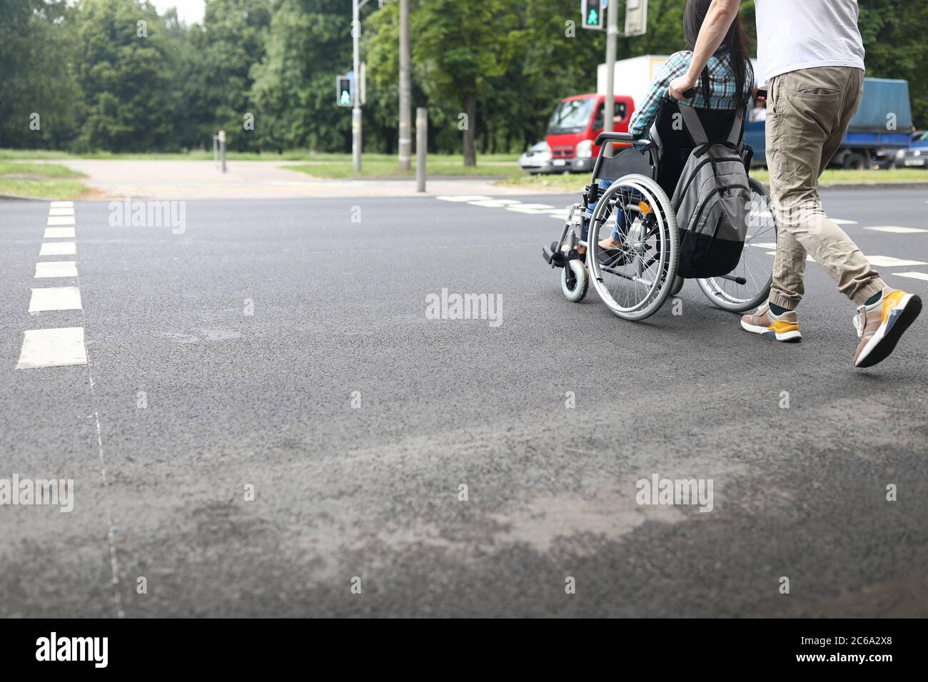 Man rolls woman in wheelchair across the road Stock Photo - Alamy