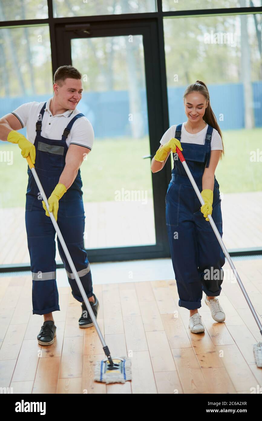 Two coleagues of cleaning company cheerfully cleaning new house ...