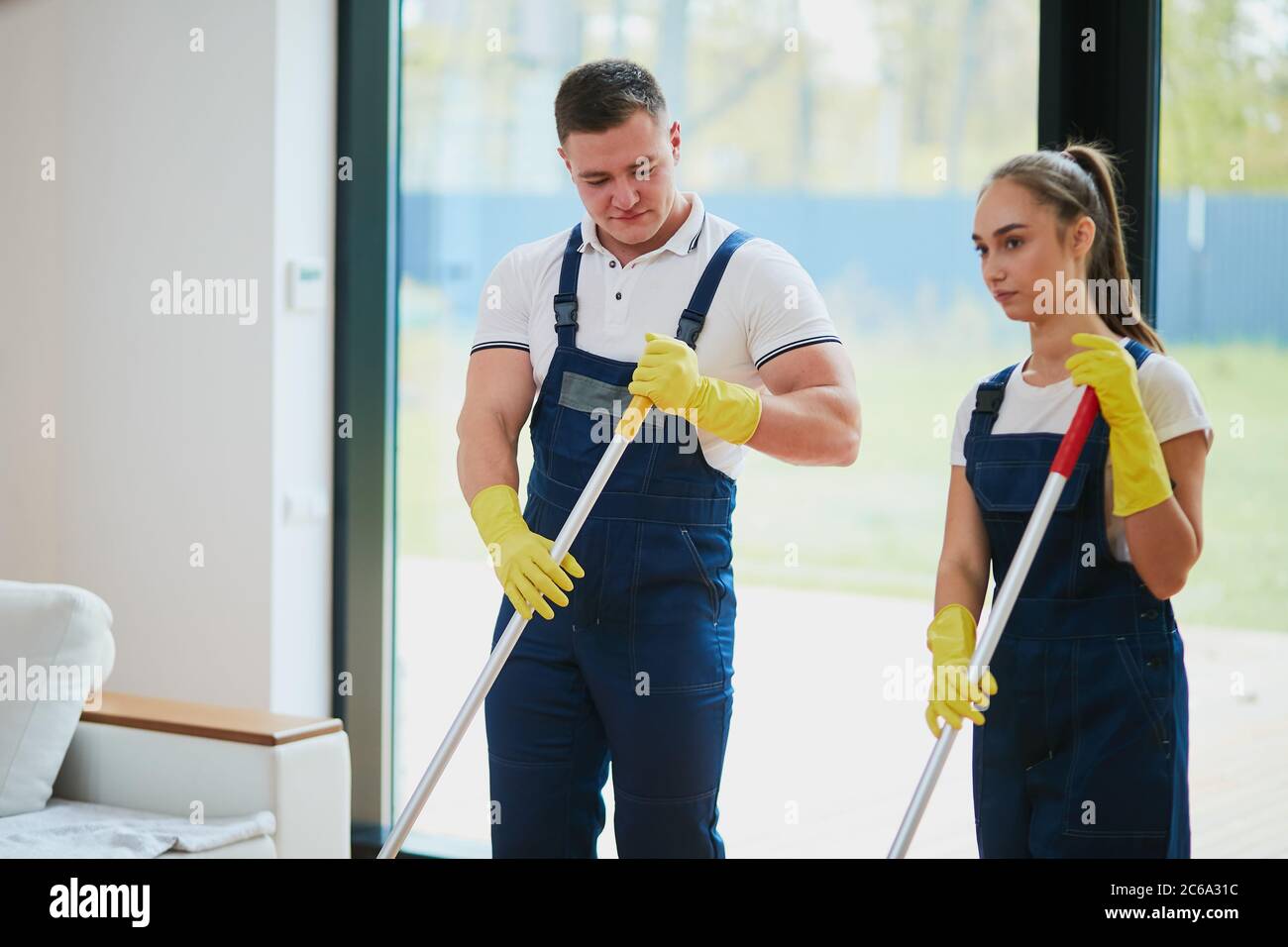 Staff of cleaning service work together, washing floor with mop ...