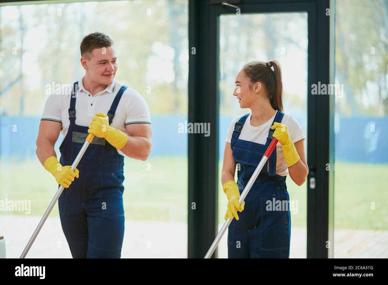 Staff of cleaning service work together, washing floor with mop ...
