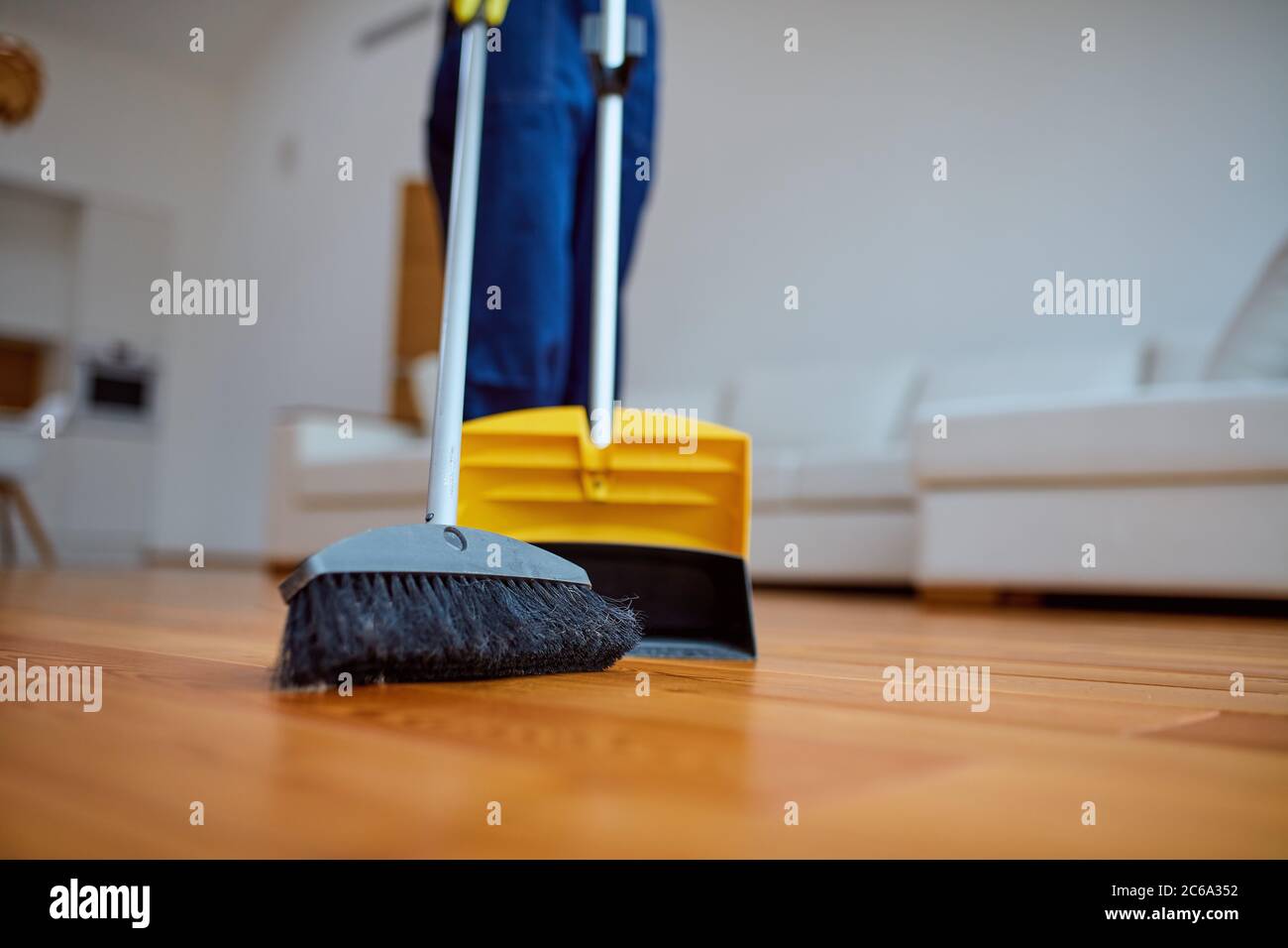 Young cleaner sweep the floor in living room. Cleaning service Stock ...