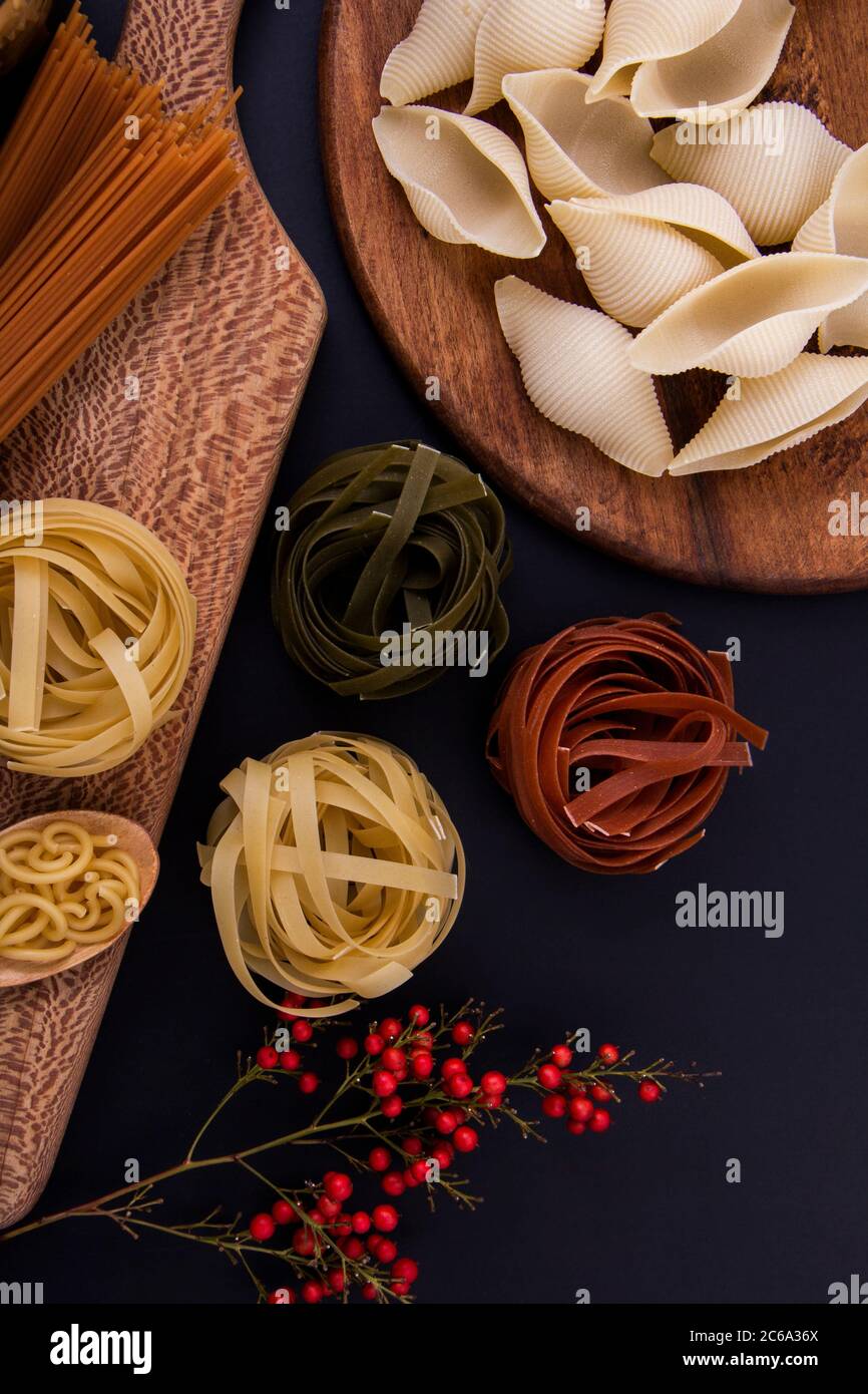 Long brown pasta and pasta with different shapes and colors with a bowl ...