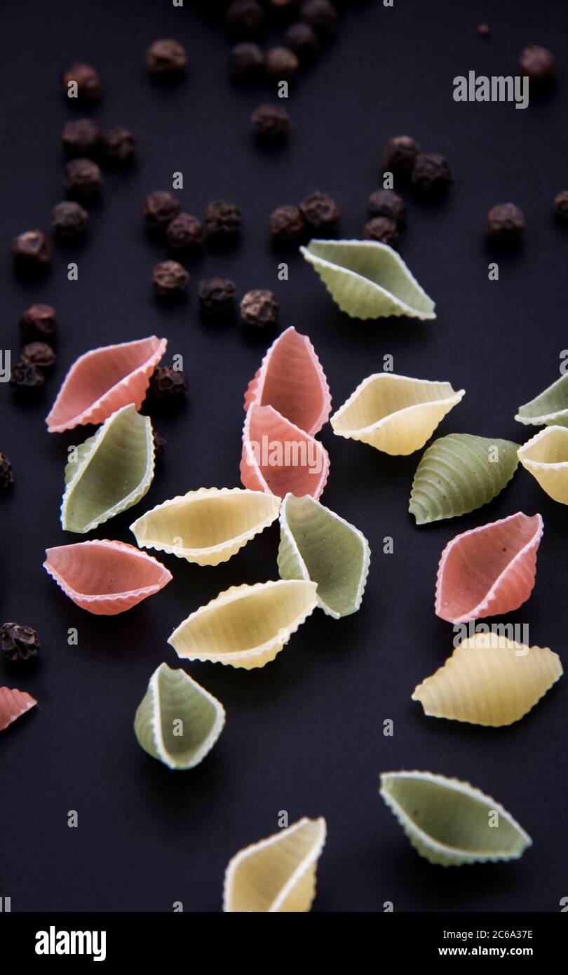 Shaped and colorful pasta in different sizes and colors next to black ...