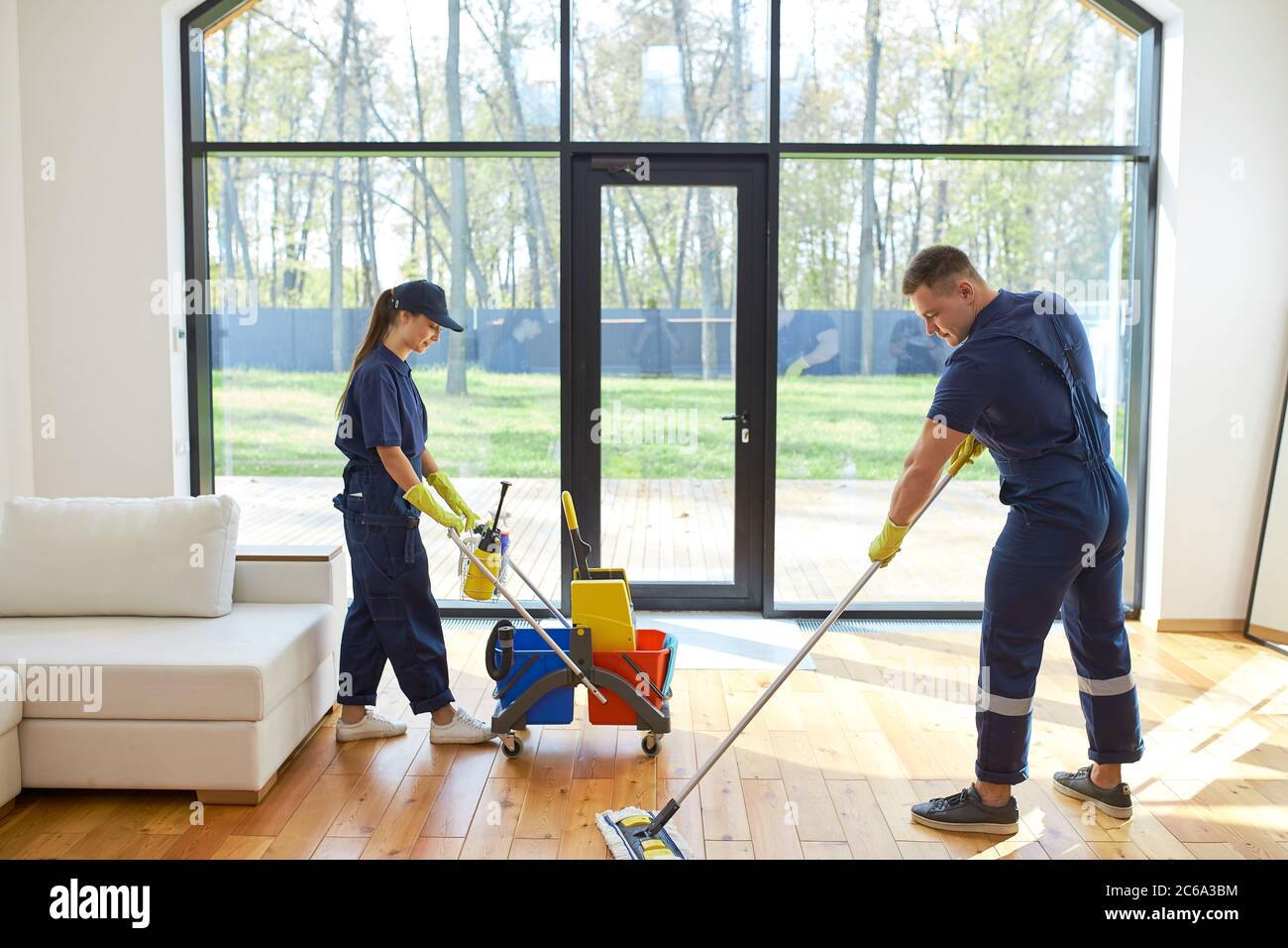 Caucasian janitors in blue uniform washing floor, using detergents ...