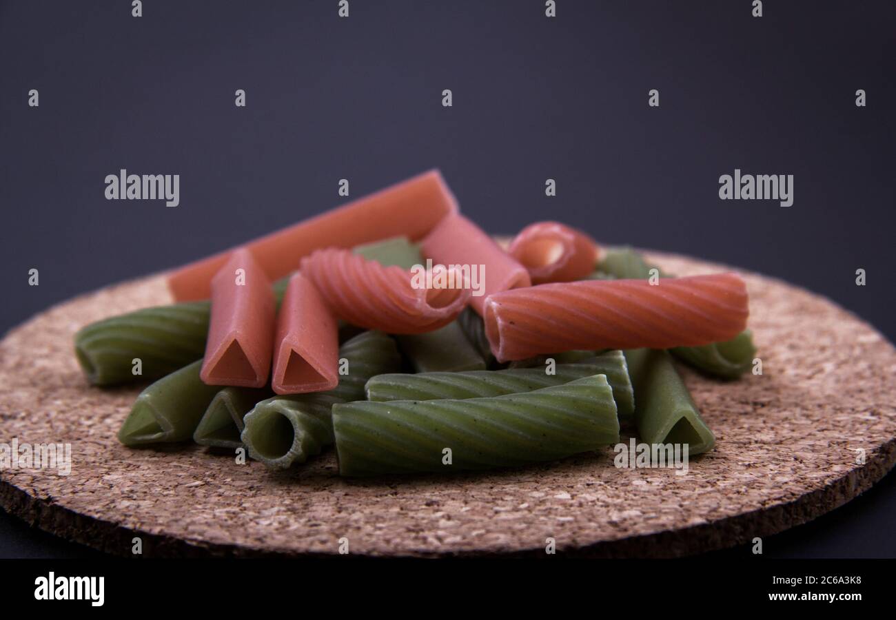 Colored pasta and pasta tubular shape in a wooden dish together Stock ...