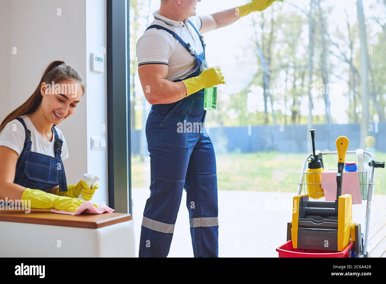 Side view on active job of two caucasian janitors dressed in uniform ...