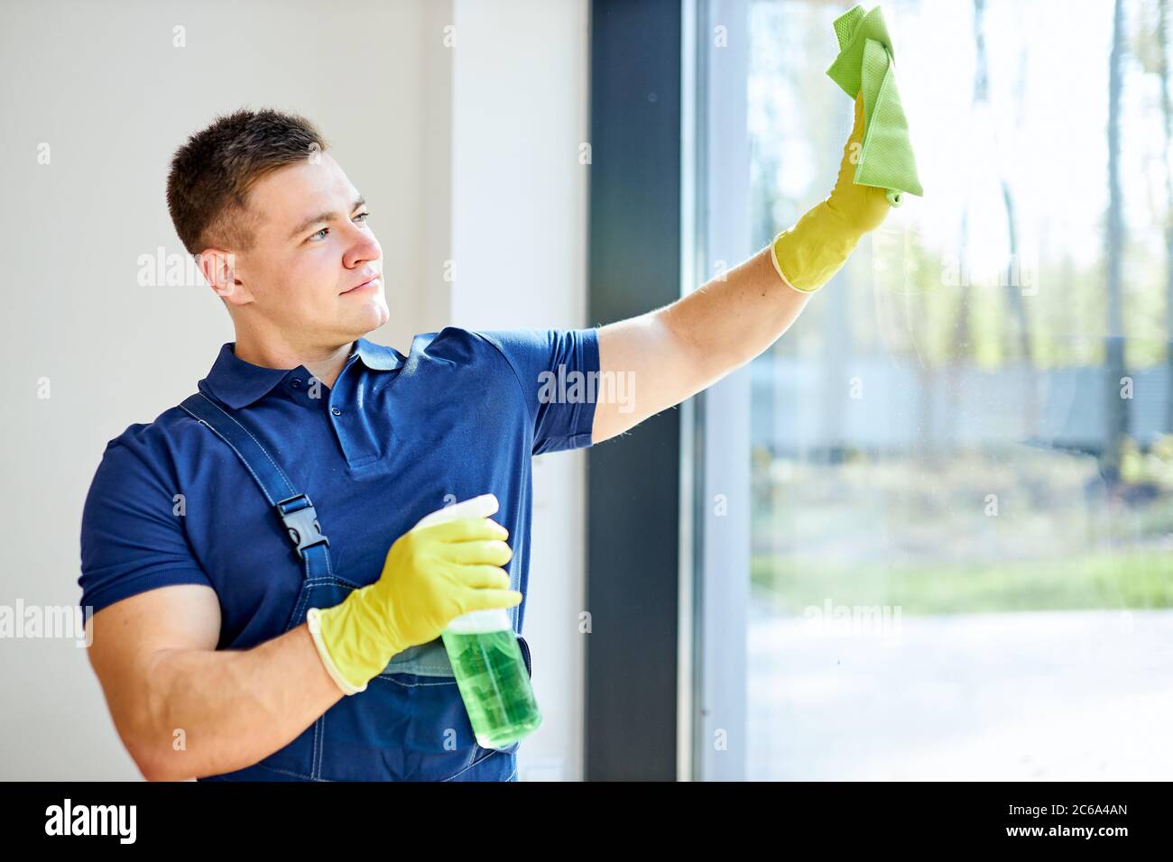 side view on attractive male cleaner wearing blue working uniform clean ...