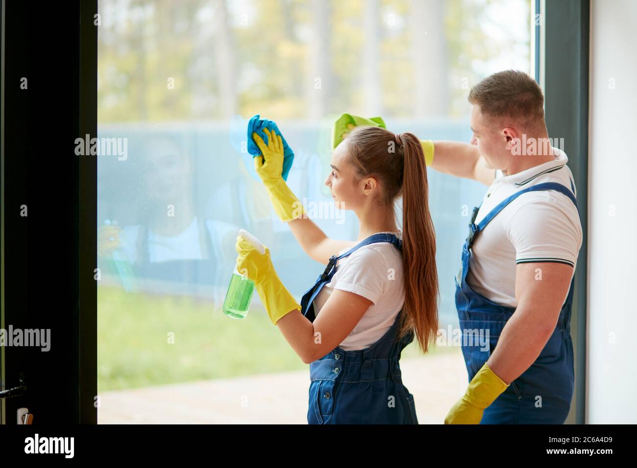 Two colleagues workers of cleaning company washing window in house ...