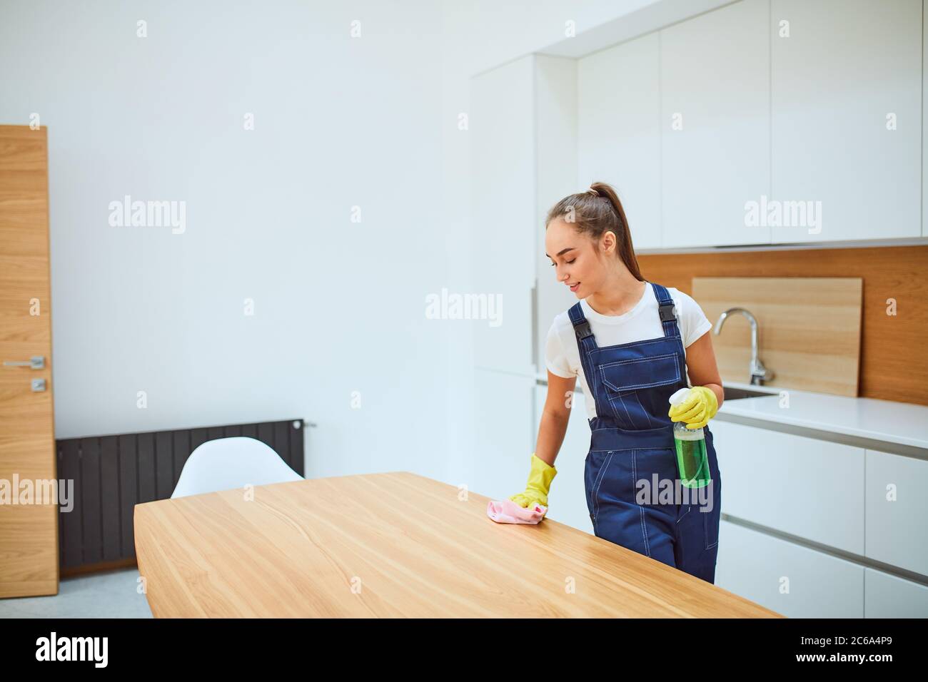 Careful female janitor wiping dust off from new table in kitchen Stock ...
