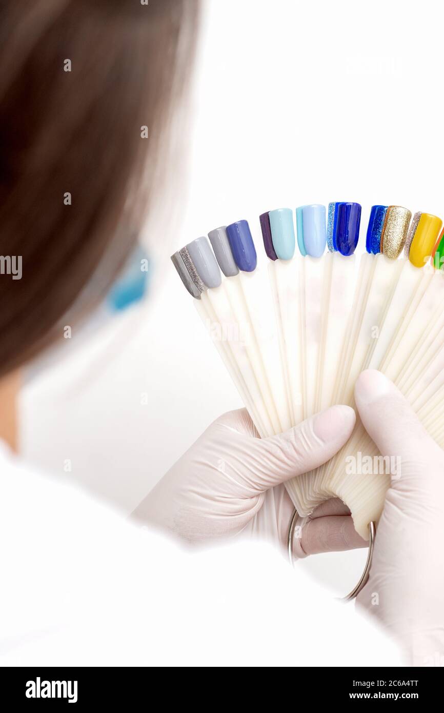 Manicurist hands are holding manicure nail color samples palette on ...