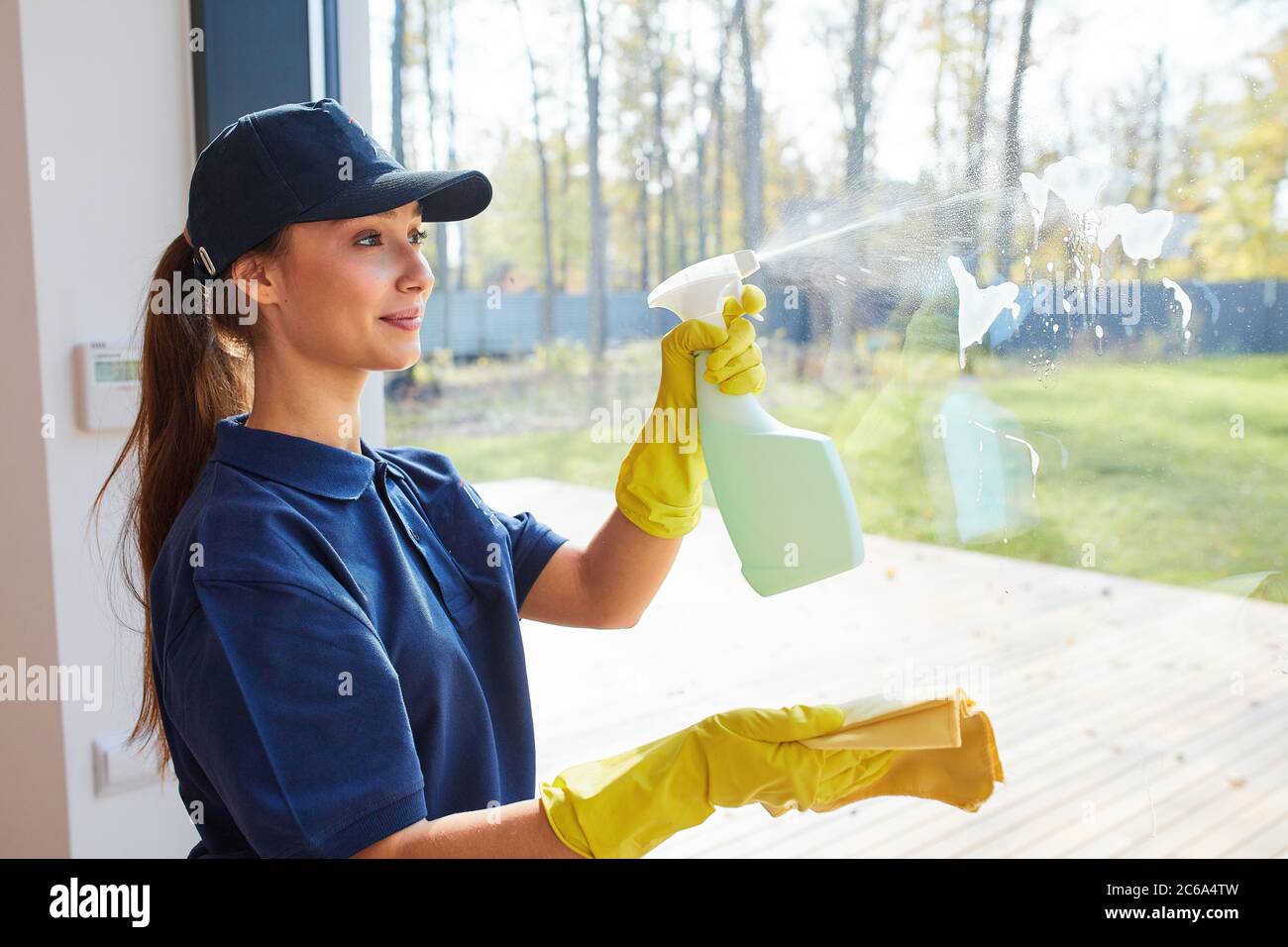 Side view on young attractive female janitor in special uniform with ...