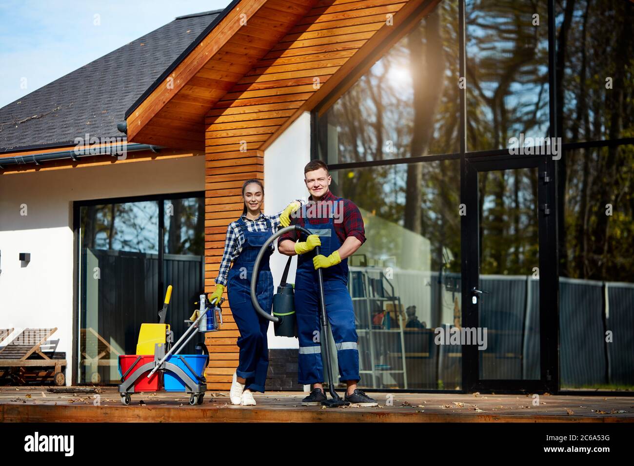 Two caucasian cleaners do perfect job, stand after cleaning house ...