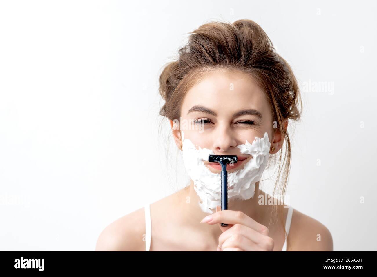 Beautiful young caucasian woman shaving her face by razor on white ...