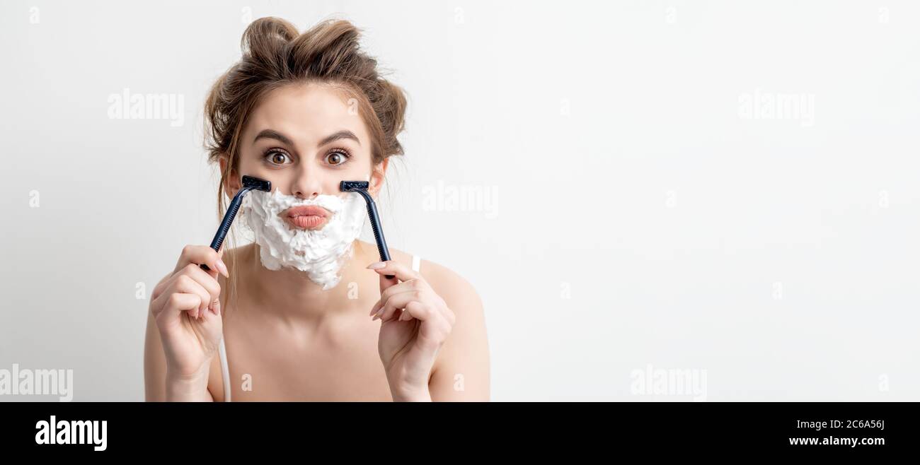 Beautiful young caucasian woman shaving her face by two razors on white ...