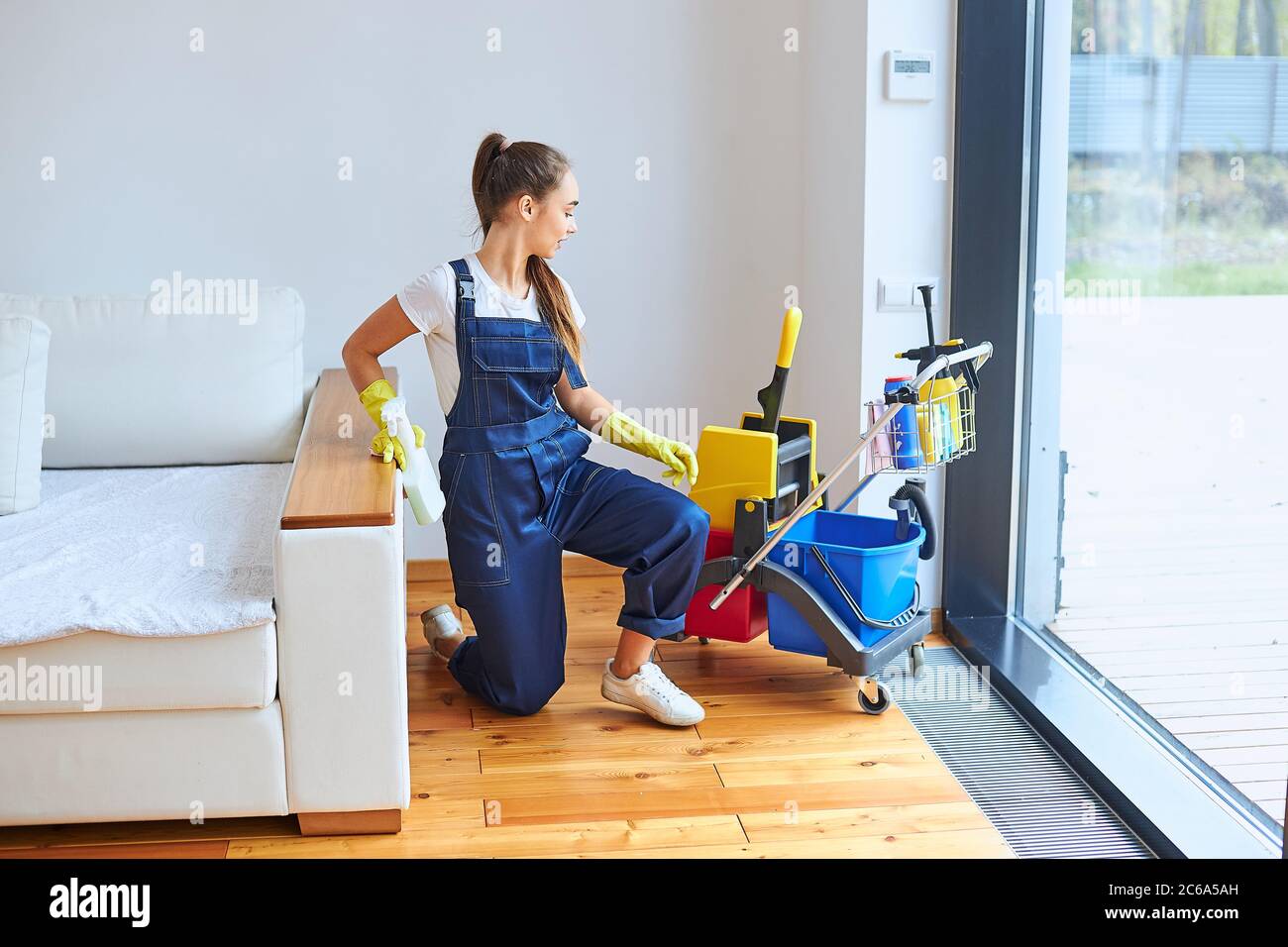 Young caucasian girl with cleaning trolley full of detergents, cleaning ...