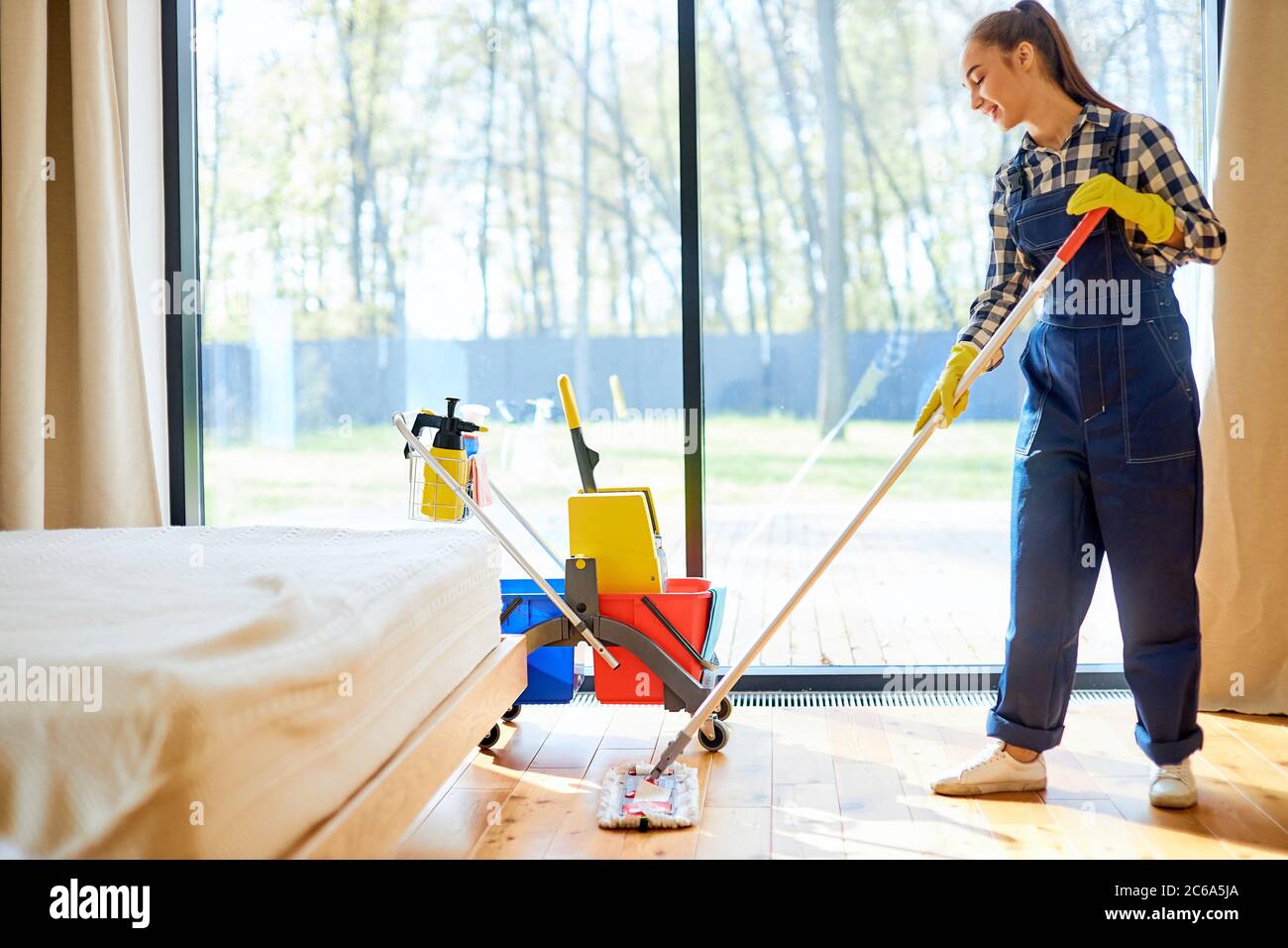 Attractive caucasian female cleaner mopping floor using detergents ...