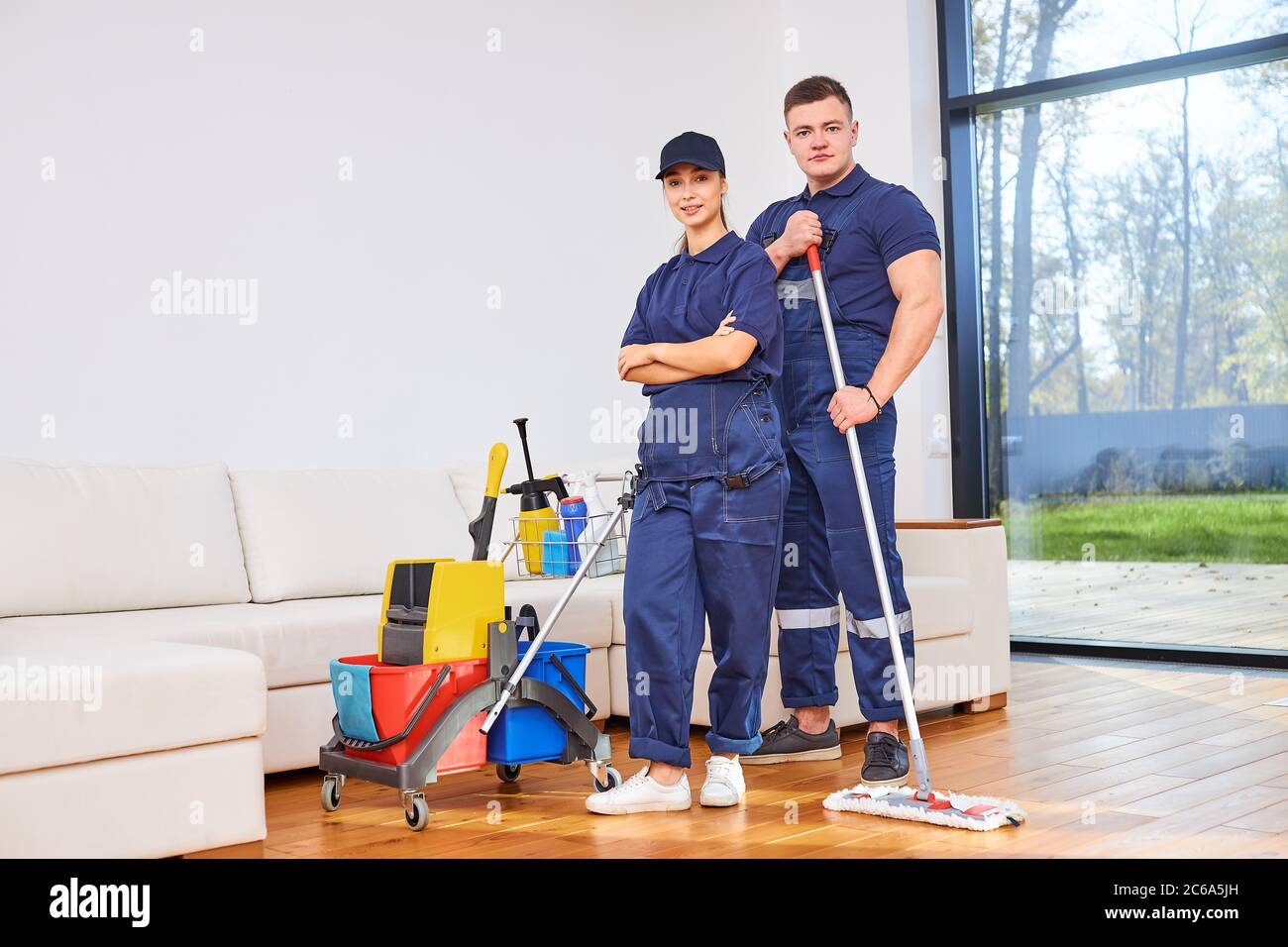 Two young members of cleaning service busy with house cleaning session ...