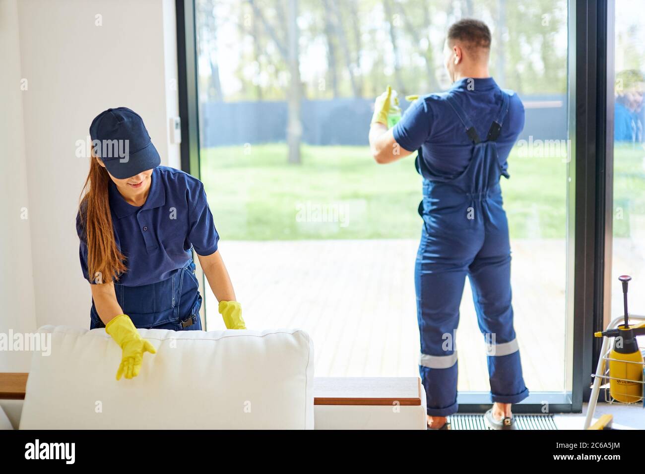 Two janitors in blue working uniform clean up roon with panoramic ...
