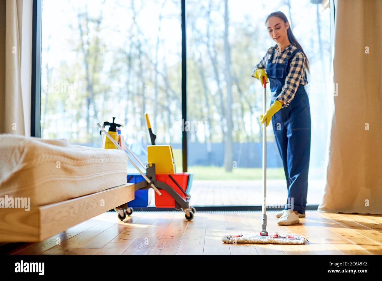 Process of mopping floor by young female in blue uniform, trolley of ...