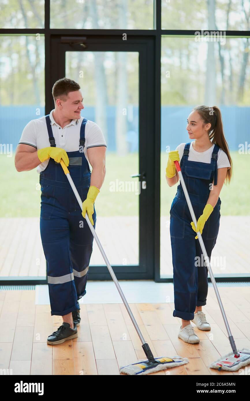 Two coleagues of cleaning company cheerfully cleaning new house ...