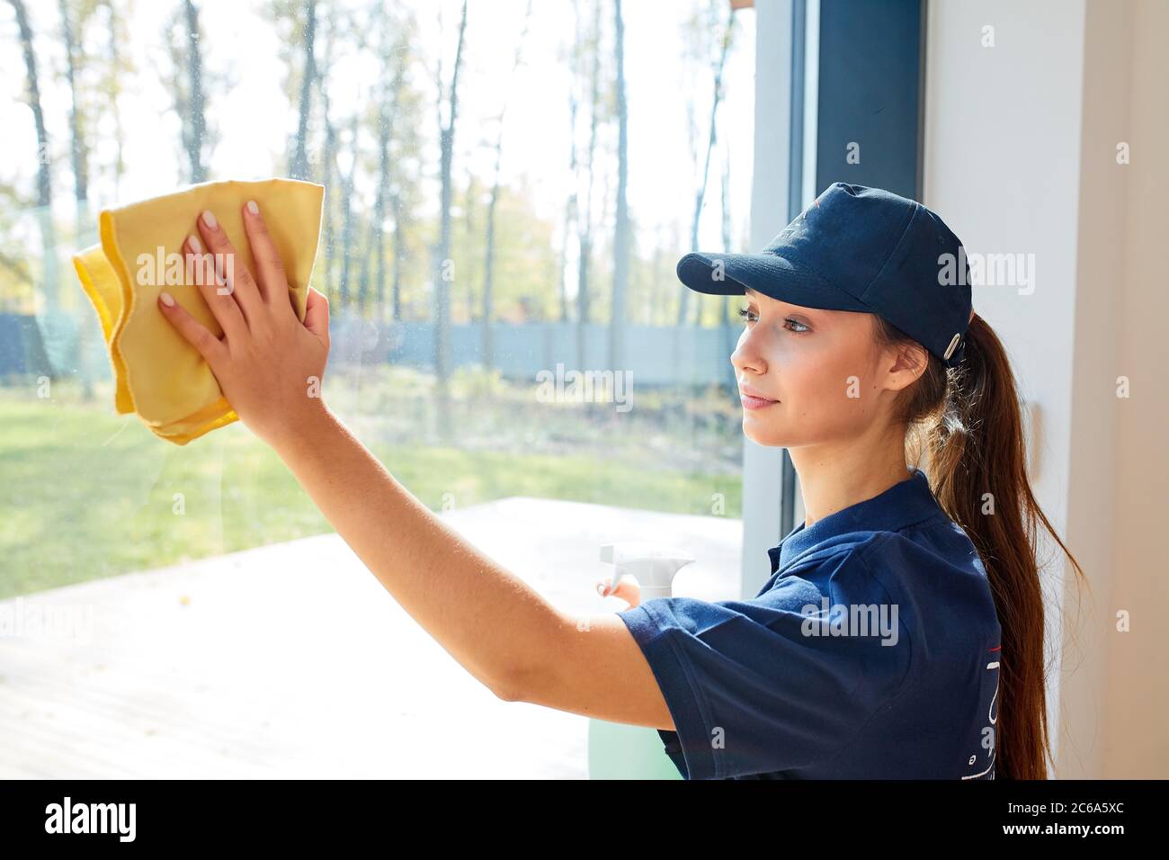 Side view on young attractive female janitor in special uniform with ...