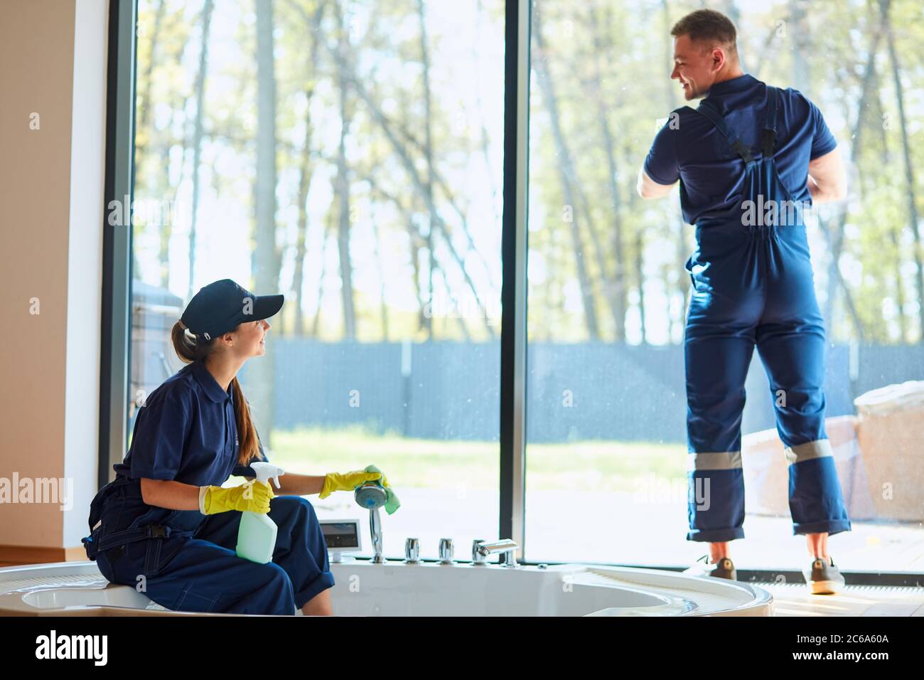 Caucasian young cleaners wearing uniform do spring-cleaning in bathroom ...
