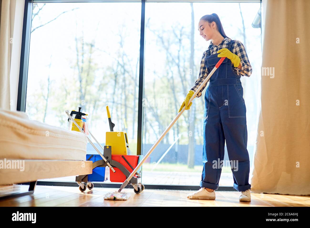 Attractive caucasian female cleaner mopping floor using detergents ...