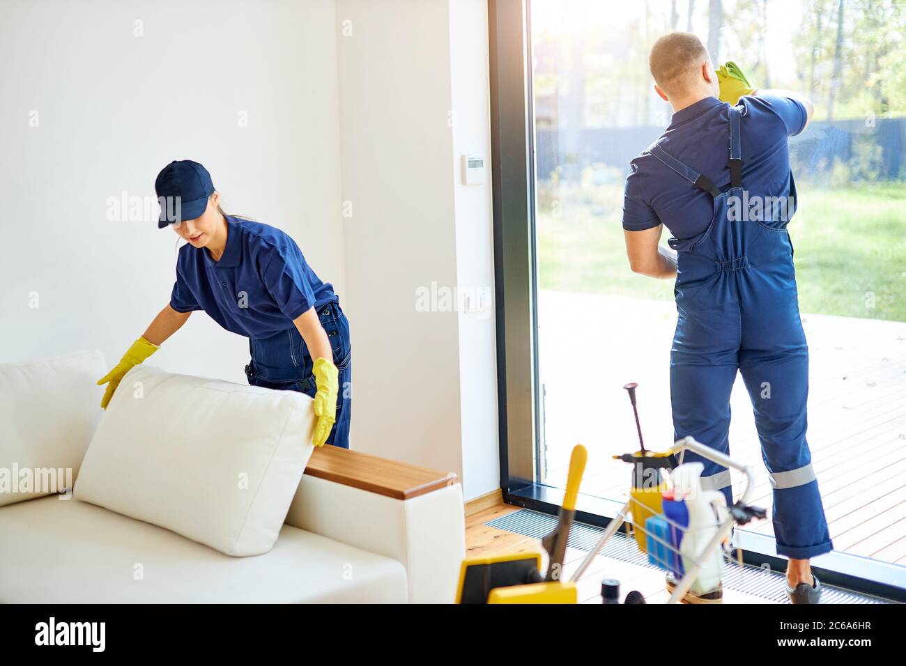 Two janitors in blue working uniform clean up roon with panoramic ...
