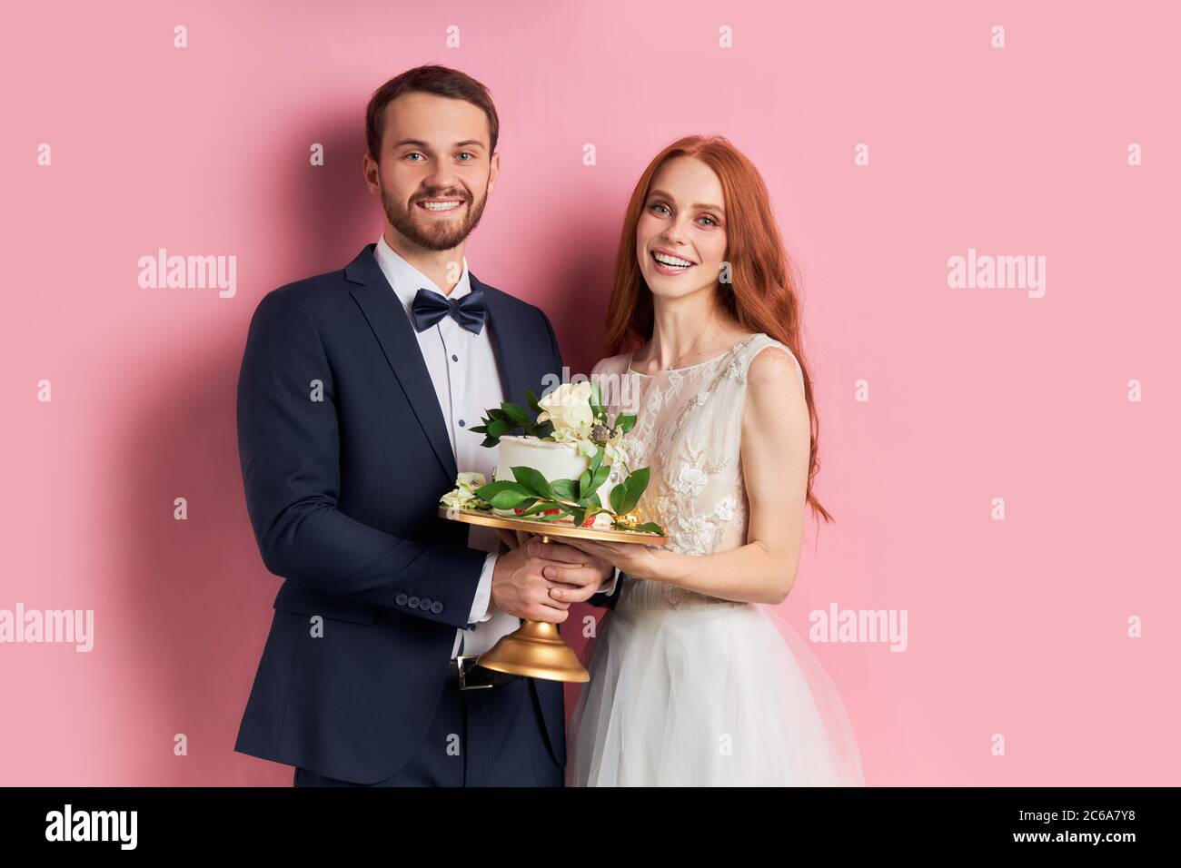 Nice young couple newly get married isolated over pink background ...