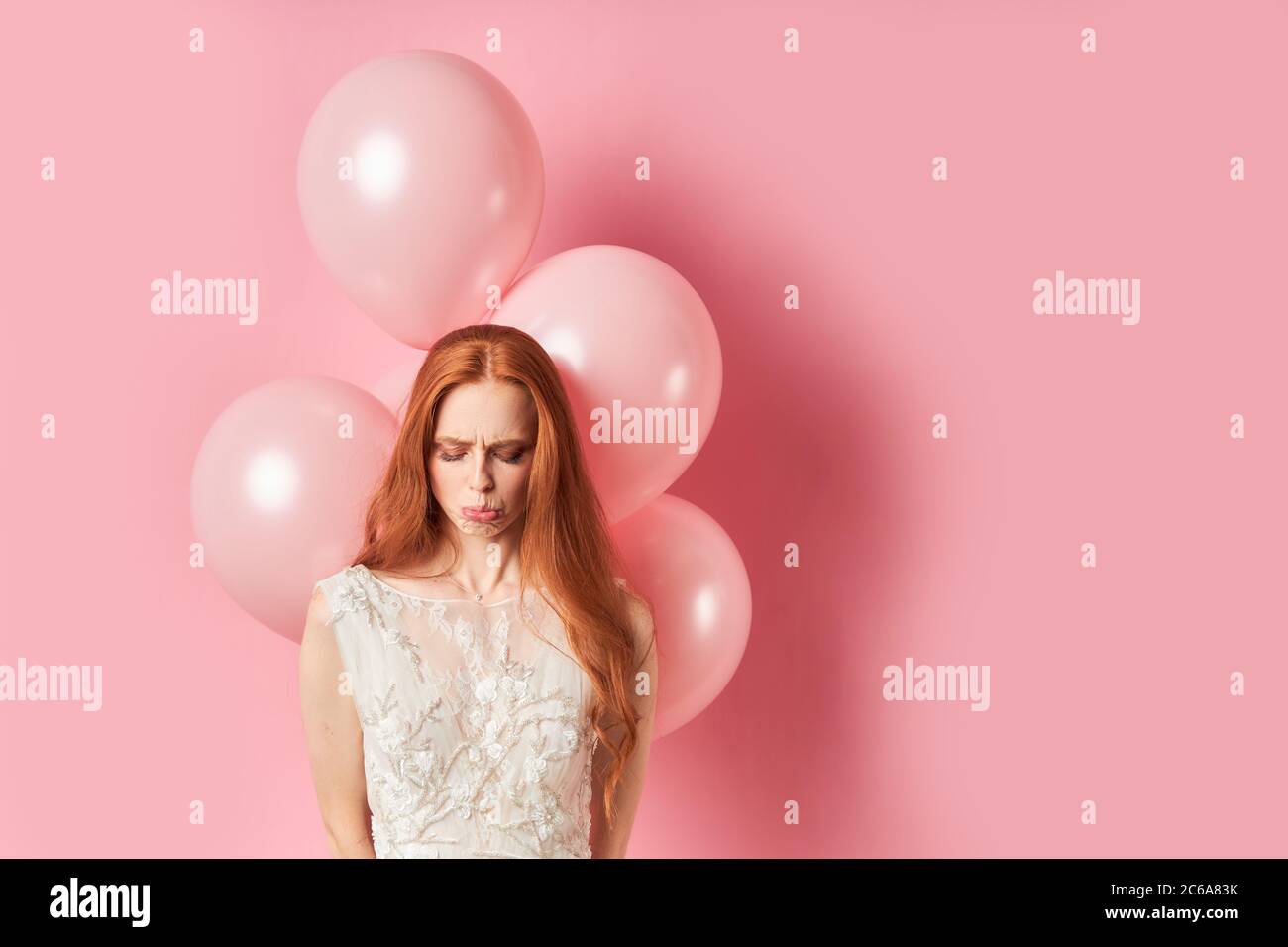 Young female with auburn hair stand sadly looking at floor, sadness ...