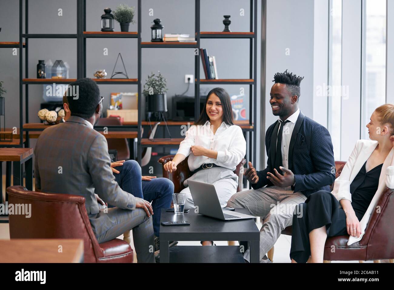Cheerful business team sitting together on able discussing, smiling ...