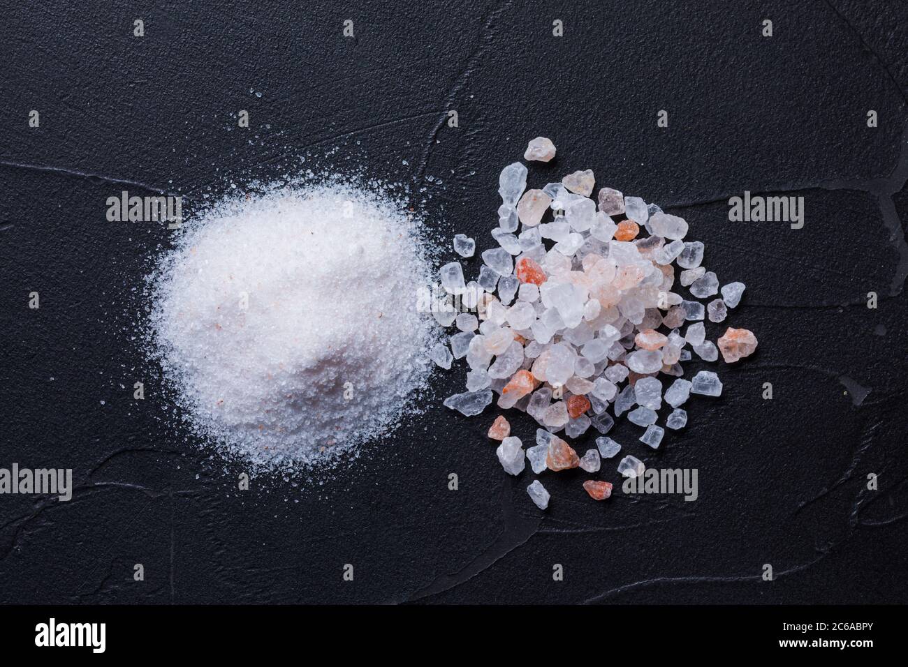 Two types of salt on black background Stock Photo - Alamy