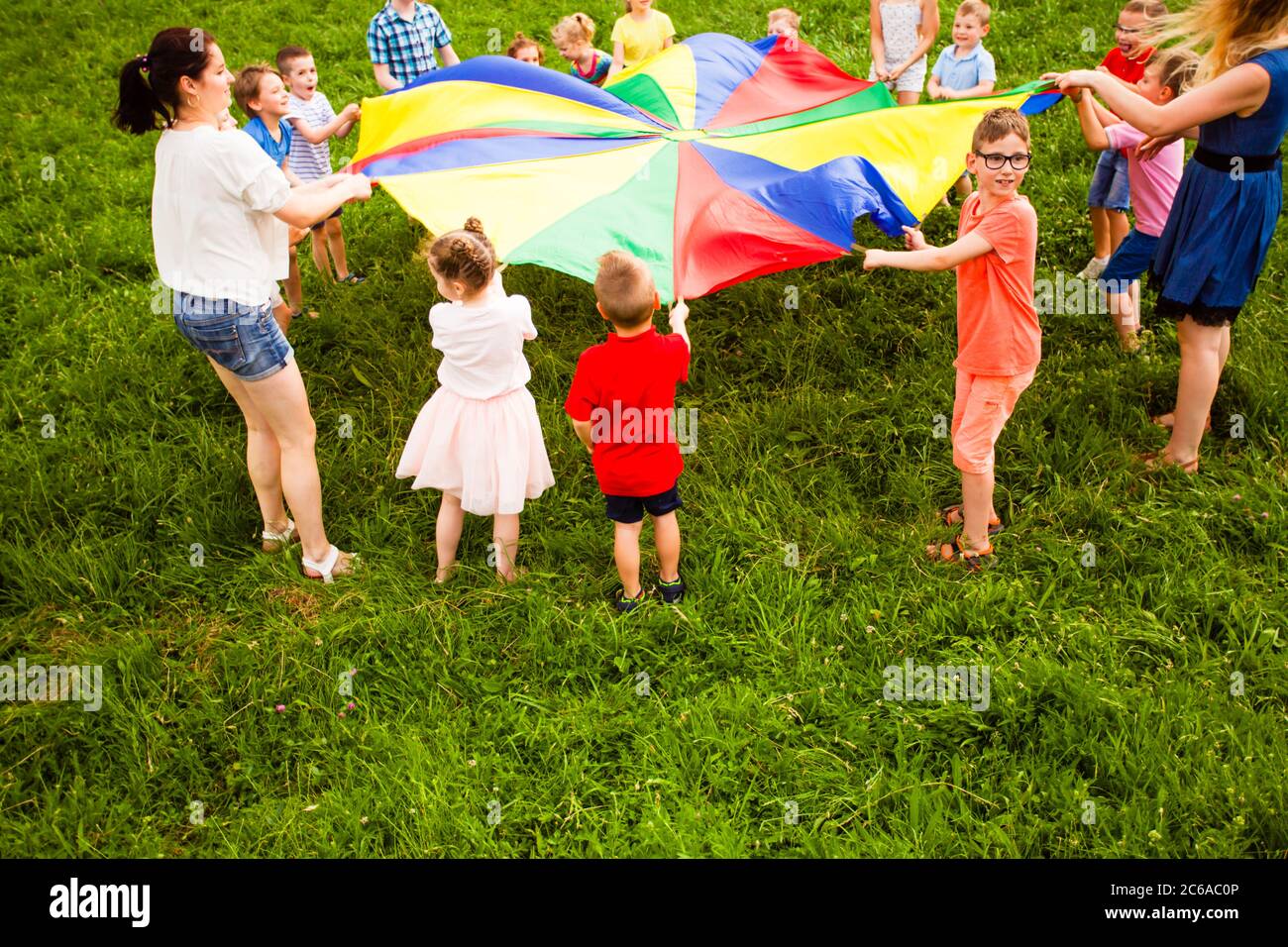 Close view children holding large colorful parachute Stock Photo - Alamy